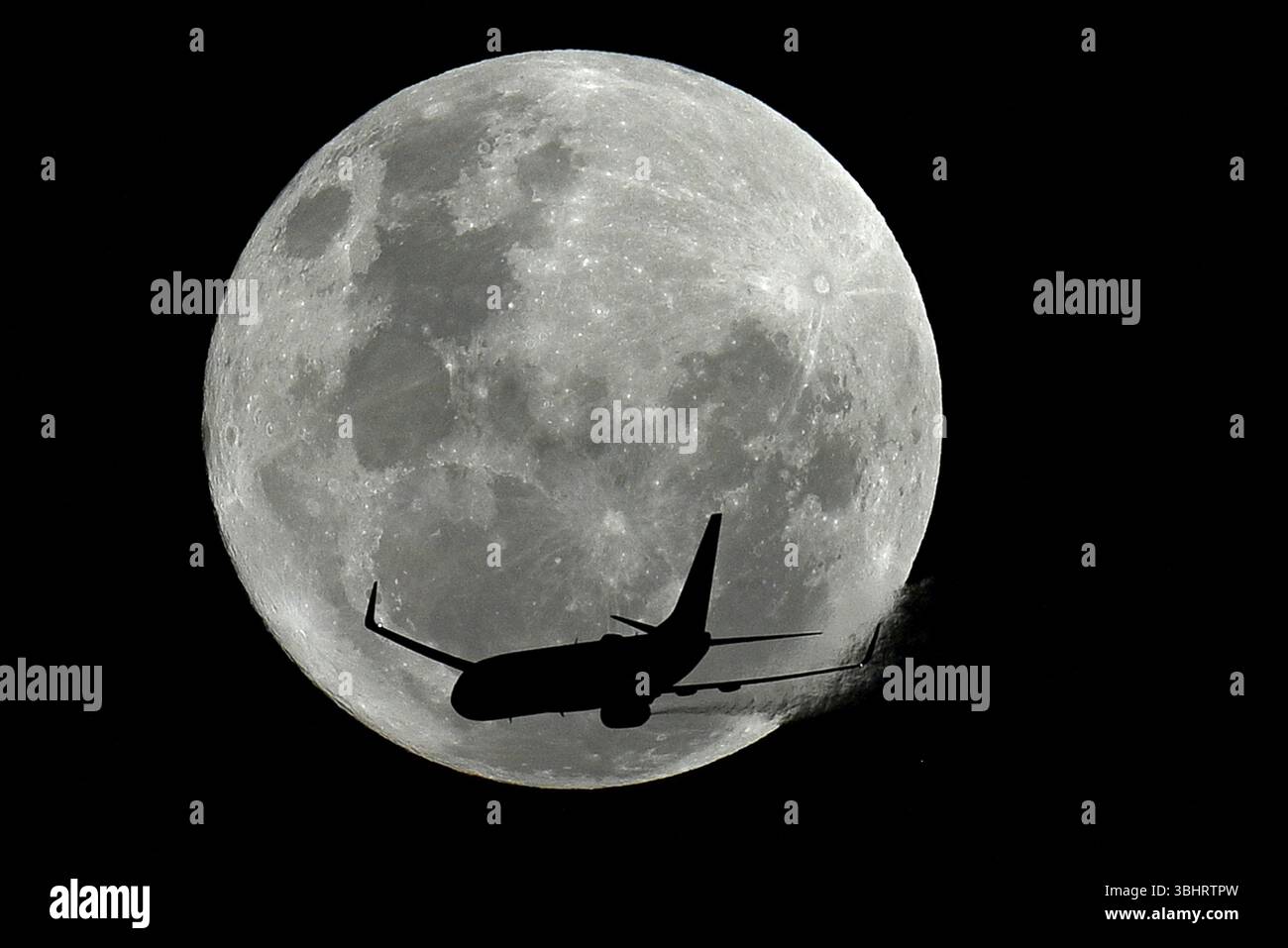 An aircraft passes in front of the full moon, known as the 'Strawberry ...