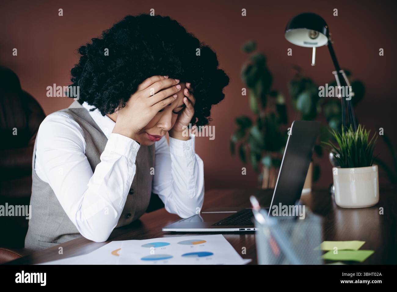 Stressed businesswoman in a modern office feeling overwhelmed by work ...