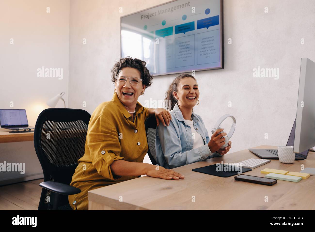Female colleagues shar a friendly moment in a modern office environment ...