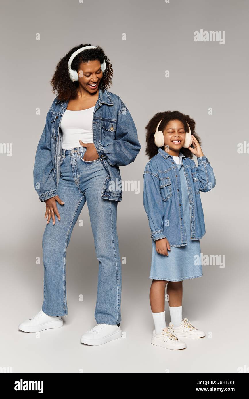 Stylish Black mom and daughter in matching denim, smiling with headphones Stock Photo - Alamy
