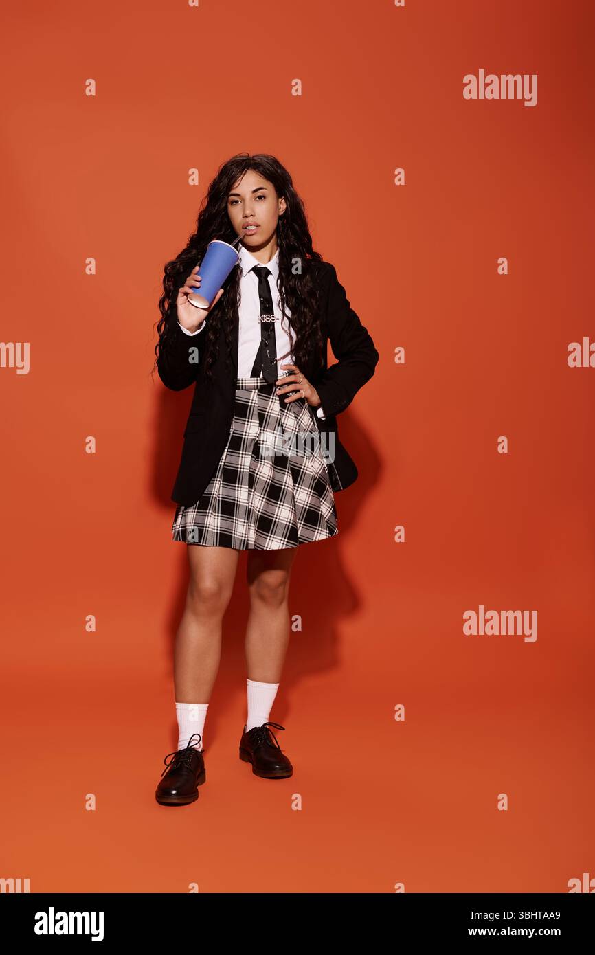 A stylish student poses confidently against a vibrant orange background ...