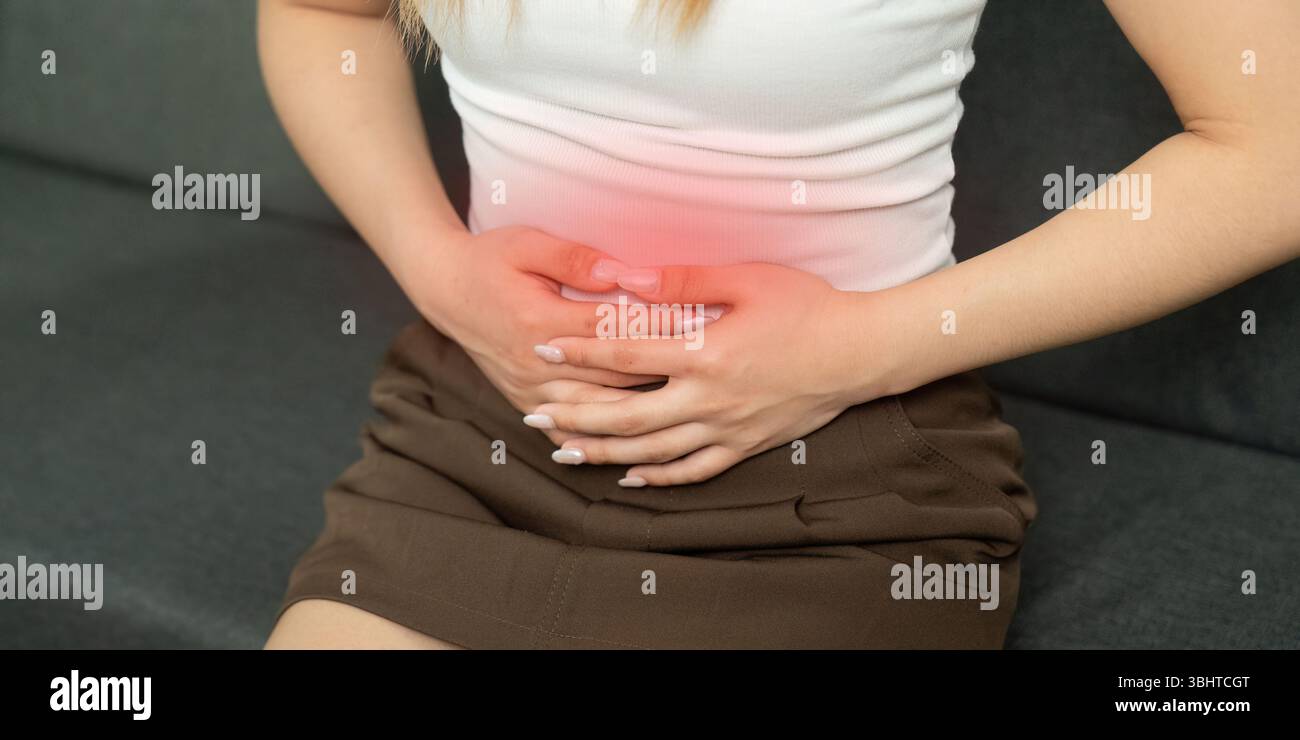 Abdominal Discomfort. Young woman holding her stomach in pain while ...