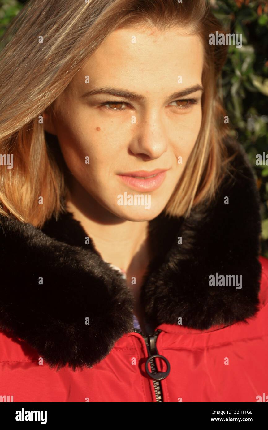 Headshot of beautiful young woman in red winter jacket with black ...
