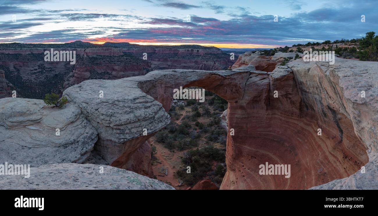 This sunset panorama features Rattlesnake Arch with a colorful sky ...