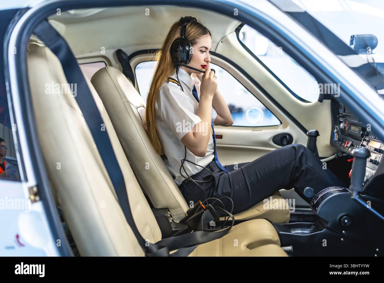 Female pilot sitting in the cockpit of a small aircraft, wearing a ...