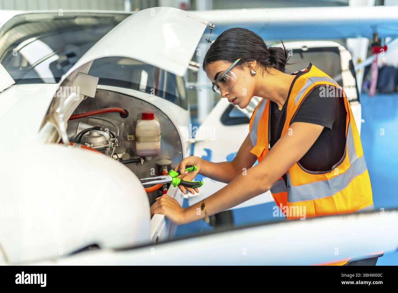 Young woman aircraft mechanic wearing safety glasses and high ...