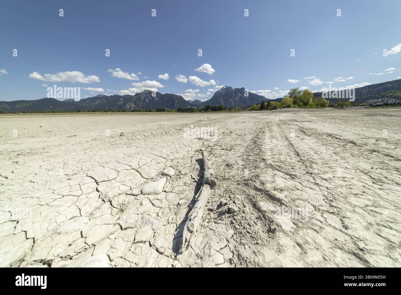 Cracked, dried out ground, waterless Forggensee in spring, behind it ...