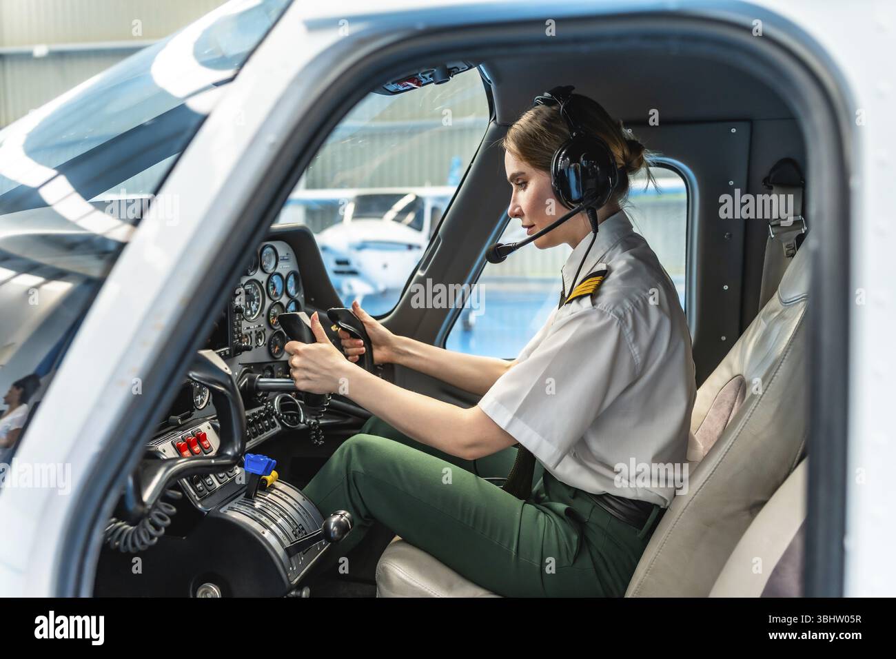 Confident female pilot wearing headset and holding steering wheel while ...
