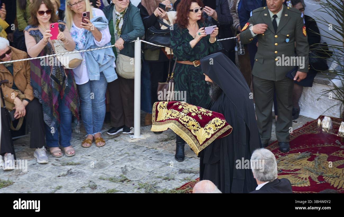 A priest in a black cloak with golden embroidery at a religious event ...