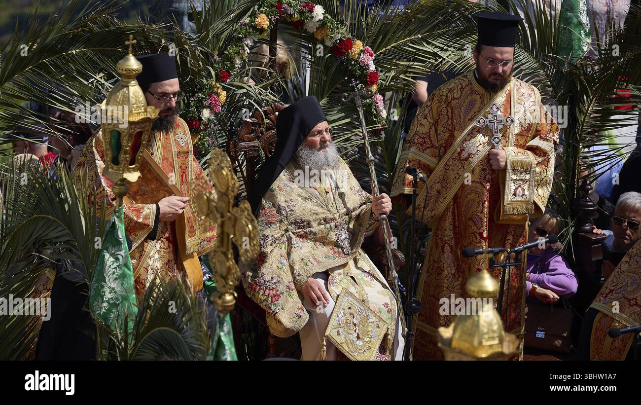 Priests in elaborate robes sit surrounded by palm trees during an ...