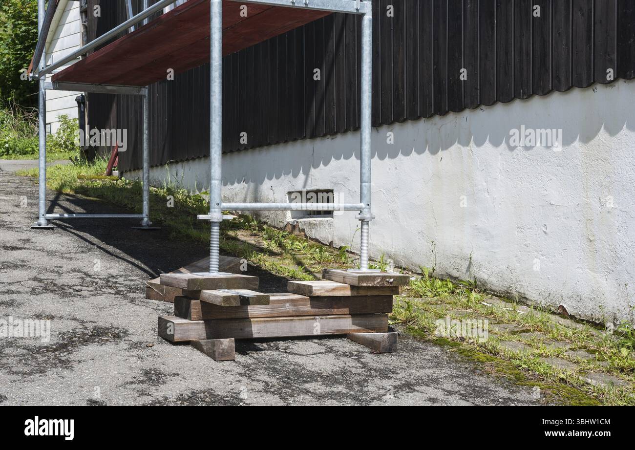 A building with a black wooden facade over a white stone base on a ...