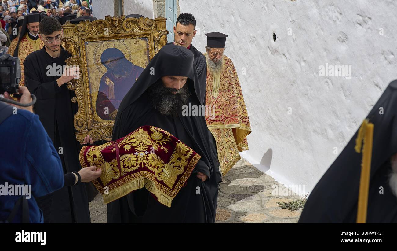 A priest in a black robe leads a procession while another carries an ...