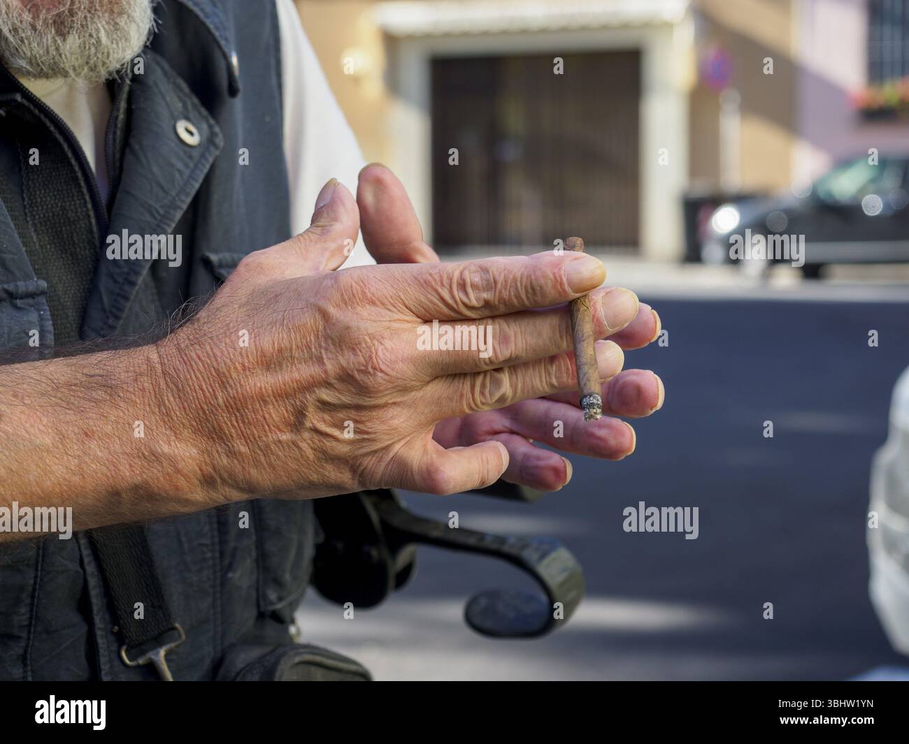 Older caucasian man sits on medical walker outdoors, smoking a cigar in ...