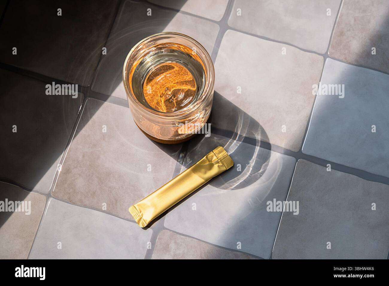 Glass of Water and Golden Sachet on a Tiled Surface. Energy Diet and ...