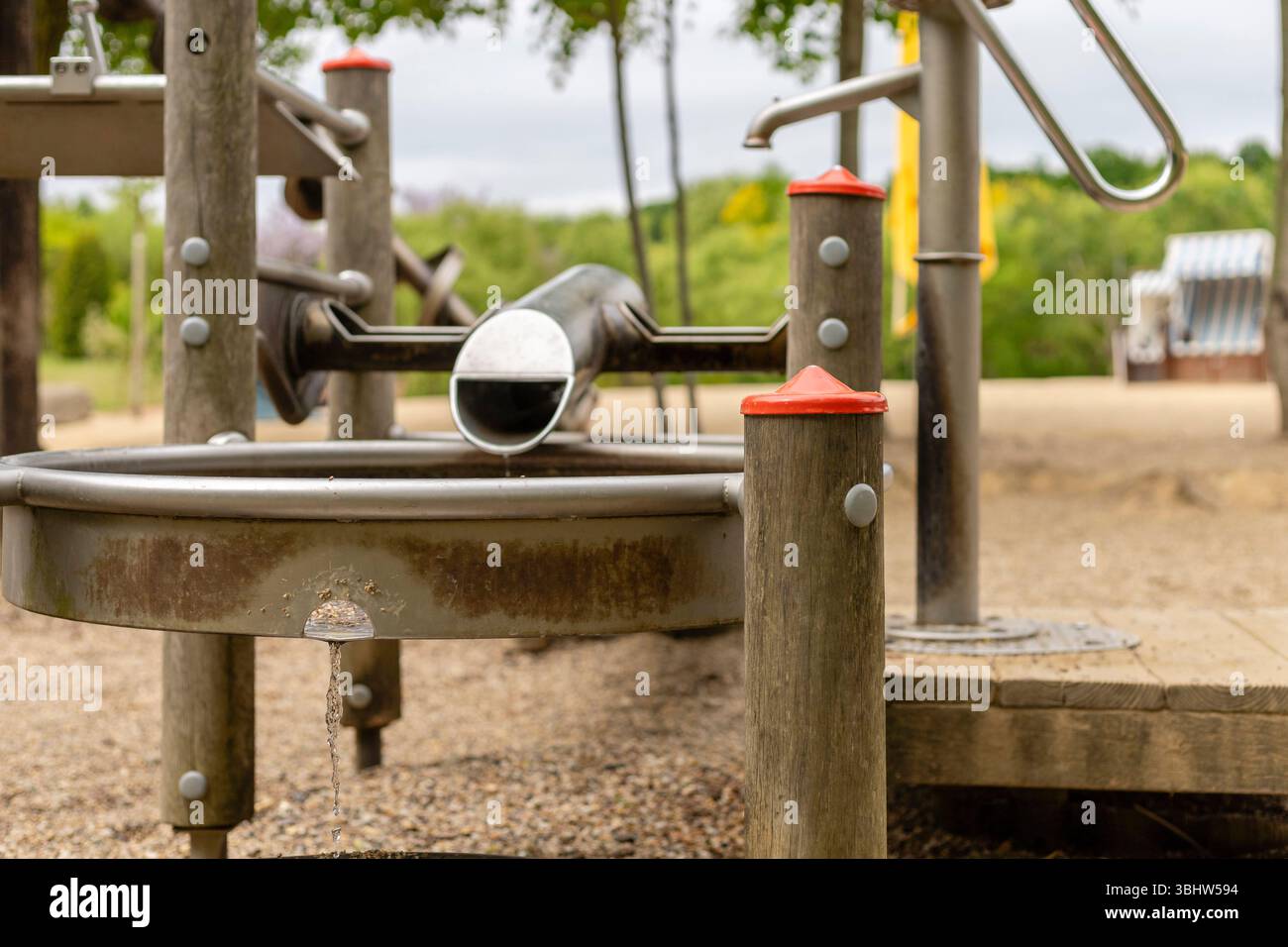 A playground area showcases a water feature with a silver pipe ...