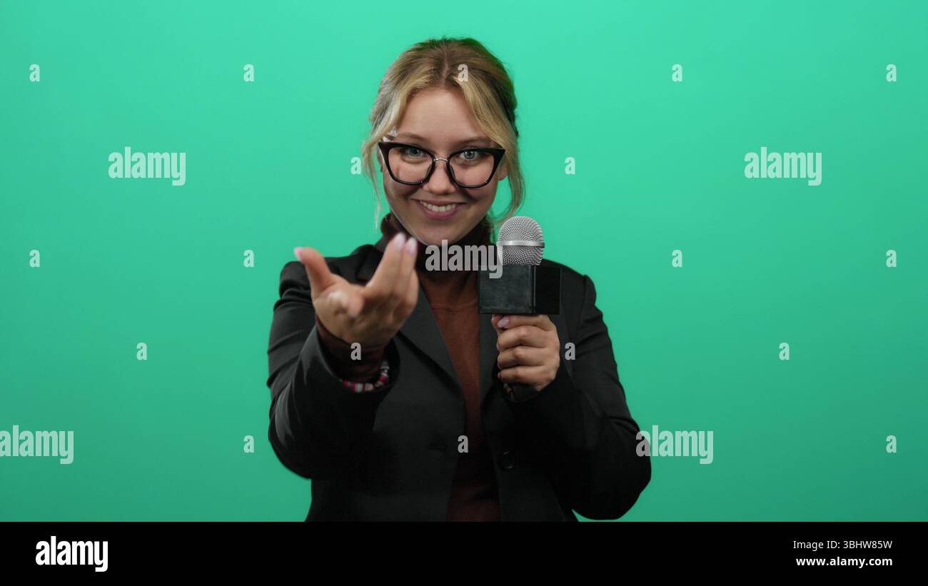 Woman reporter gesturing with a microphone against isolated green ...