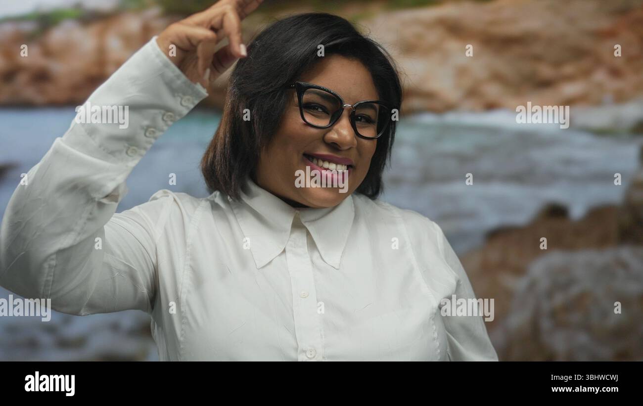 Woman smiling at seaside makes salute gesture wearing glasses with ...