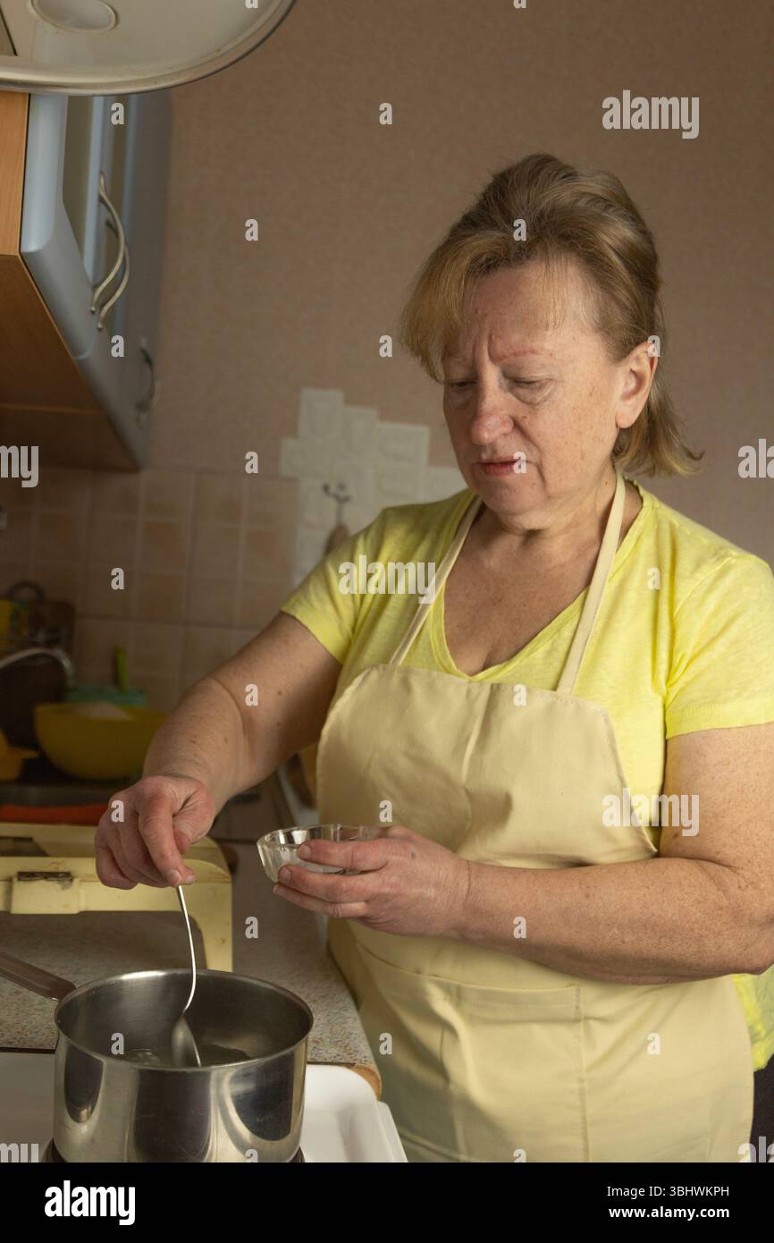 Mature woman in an apron preparing brine for homemade sauerkraut in her ...