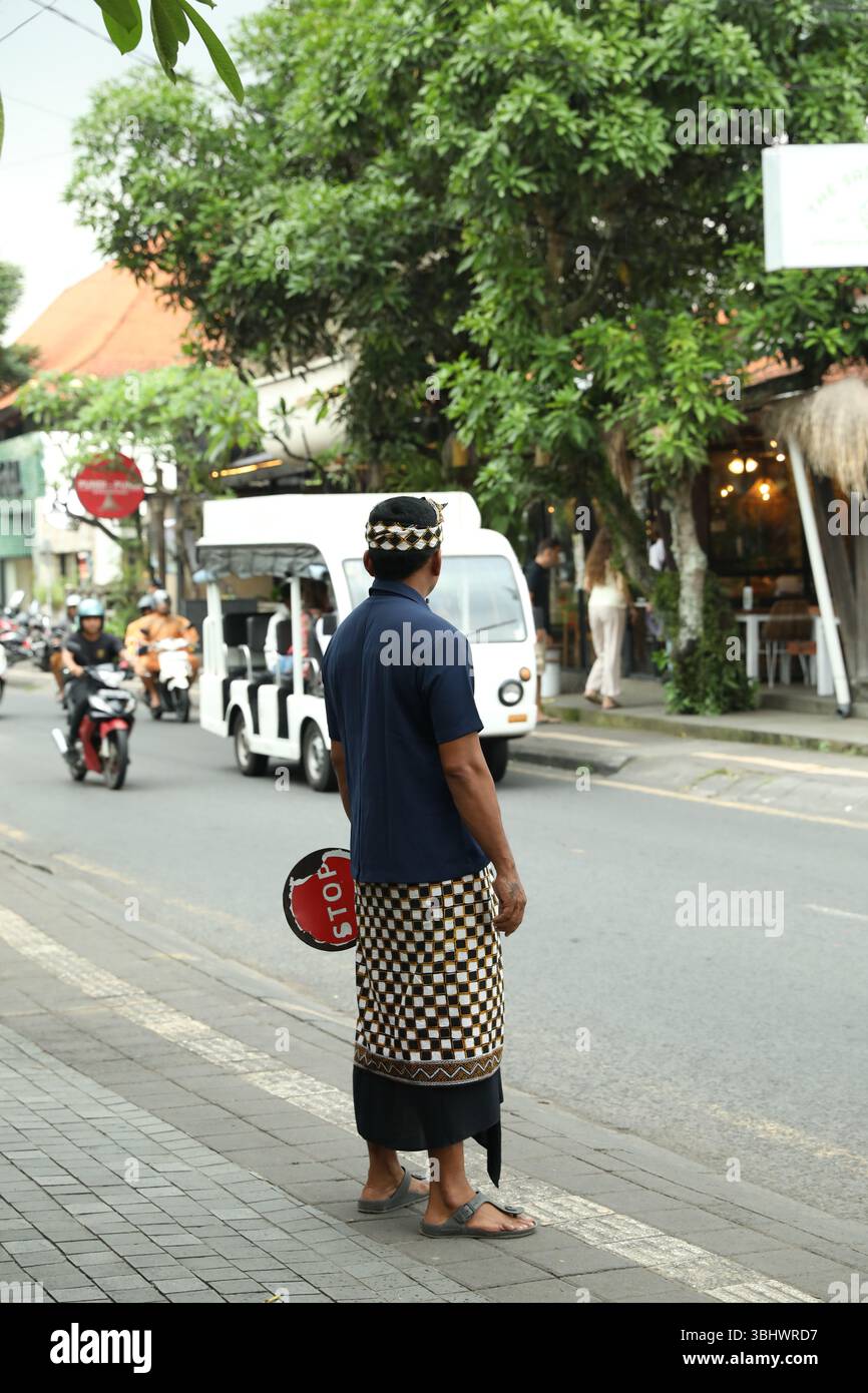 Bali, Indonesia - May 22, 2025: Traffic controller with stop sign near ...