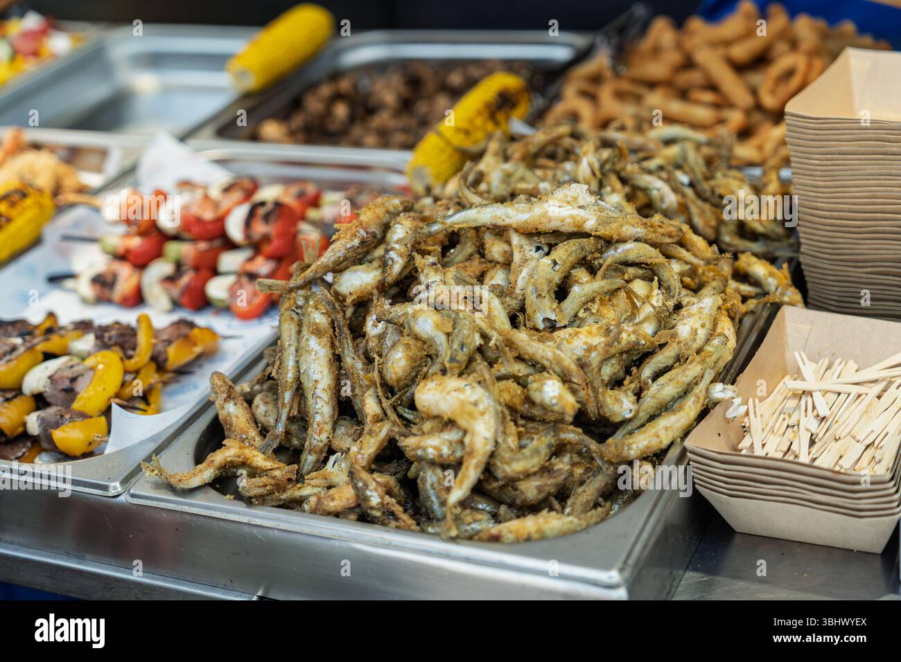 A vibrant street food stall with fried fish, grilled vegetables, and ...