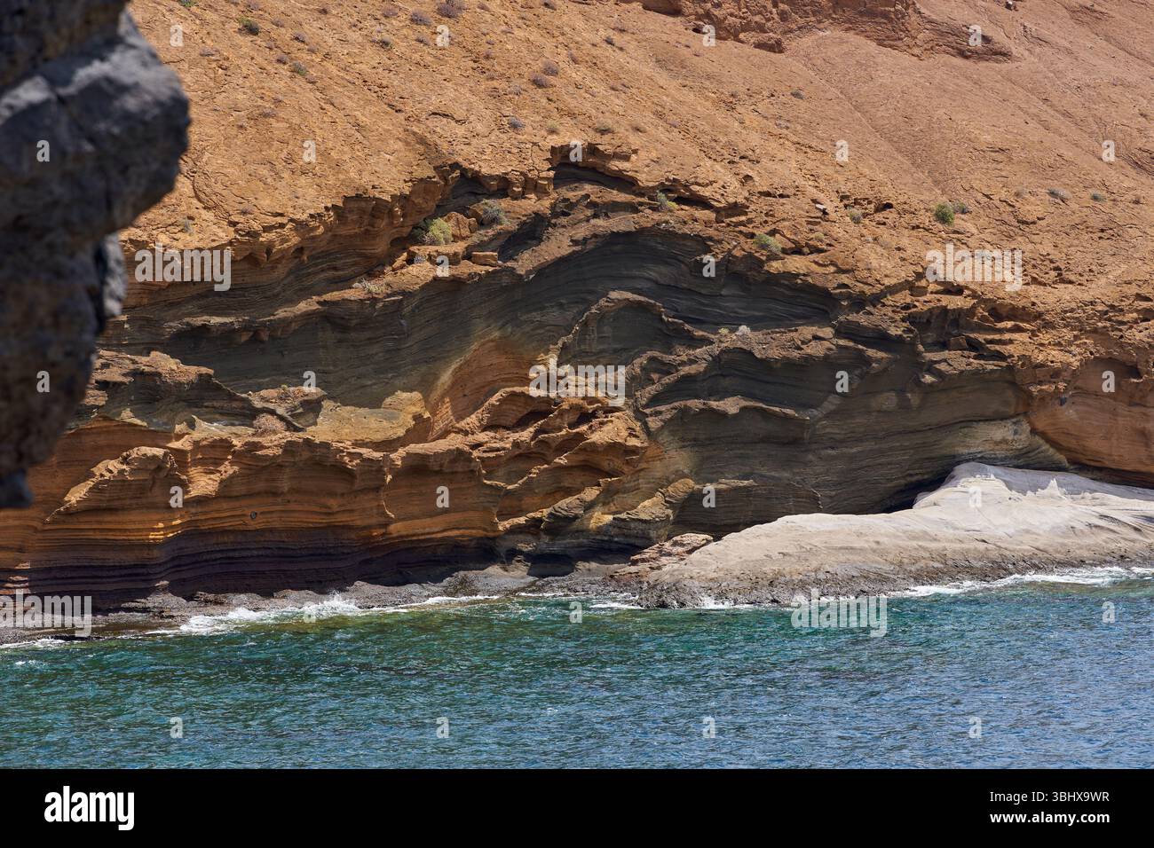 Stratified volcanic cliff above the ocean at Playa de Montaña Amarilla ...