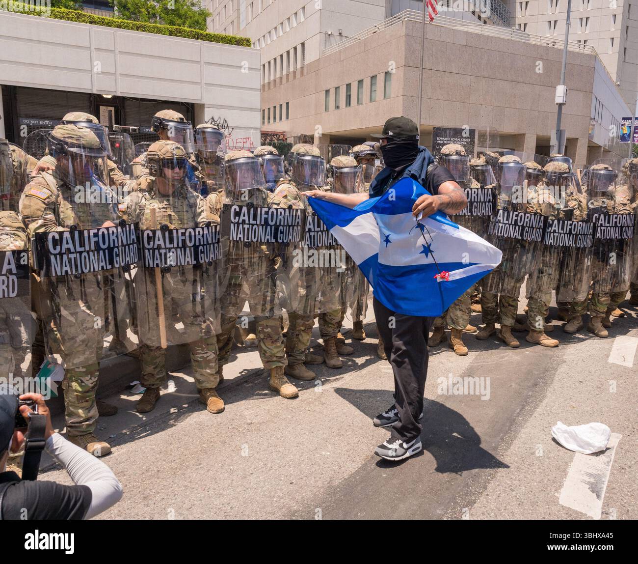 Protestor displays Honduran flag in front of National Guard members at ...