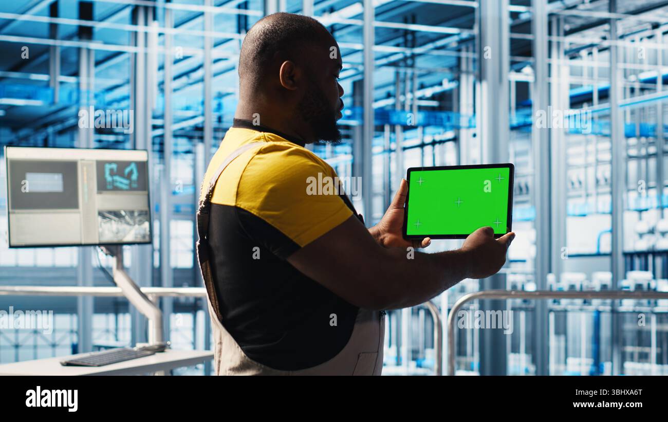 Smart factory engineer oversees operation of robotic arms and conveyor ...