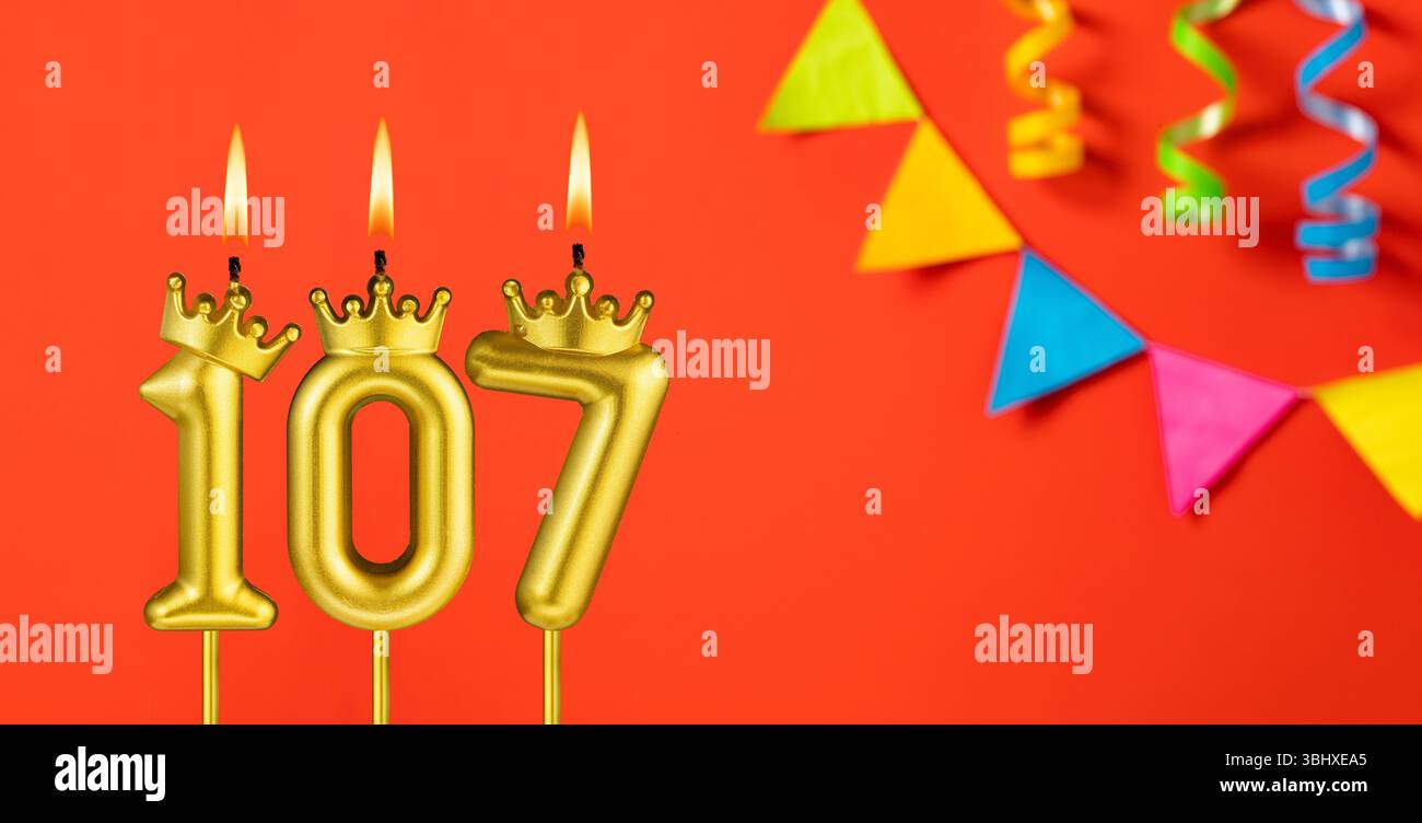 Number 107 birthday candle on an orange background with pennants Stock ...
