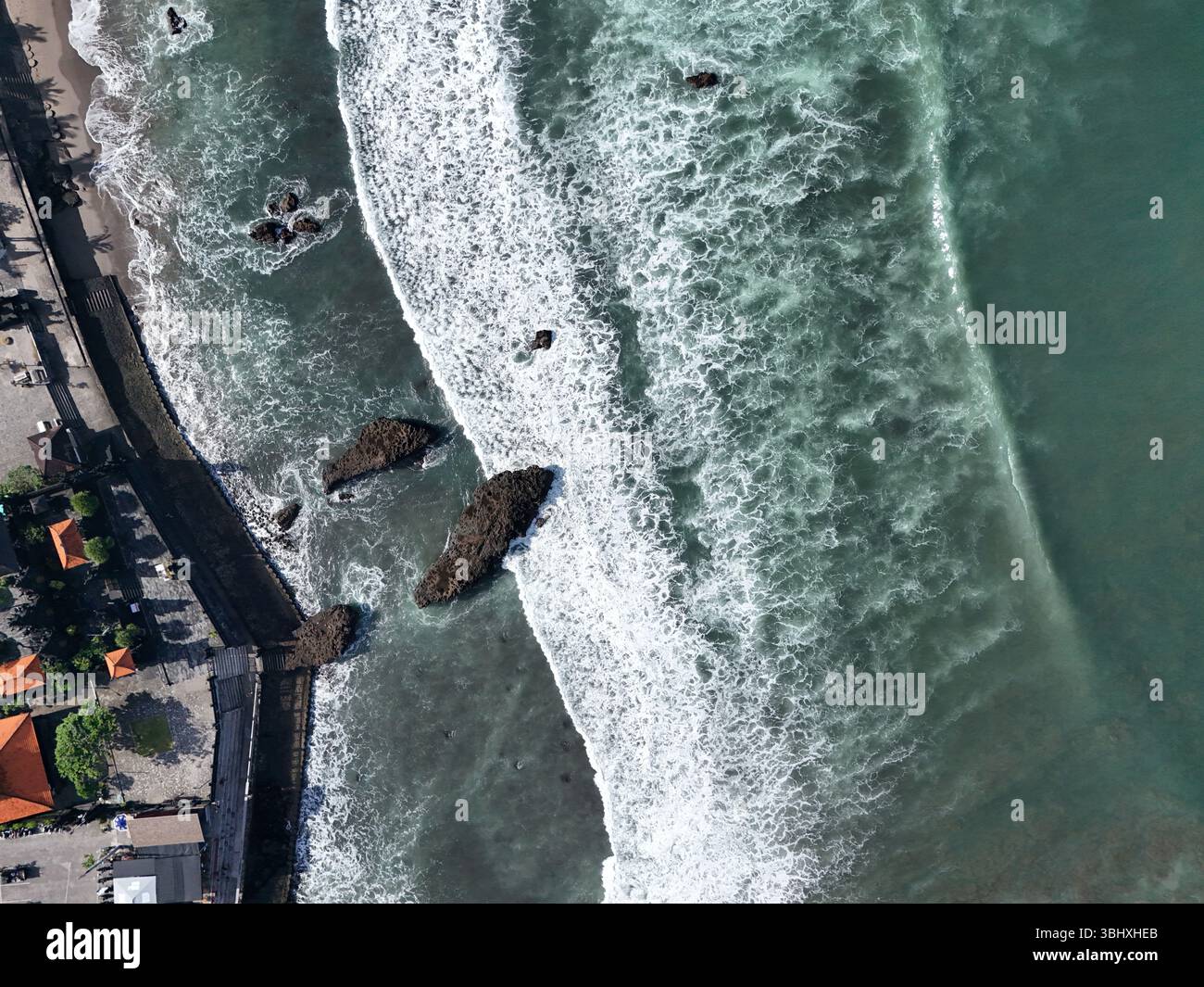 Drone aerial photo of a beach with rolling waves and large rocks on the ...