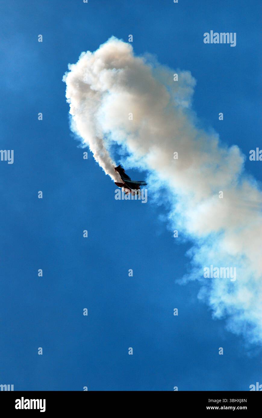A stunt pilot performs a hook maneuver in an airplane during an airshow ...
