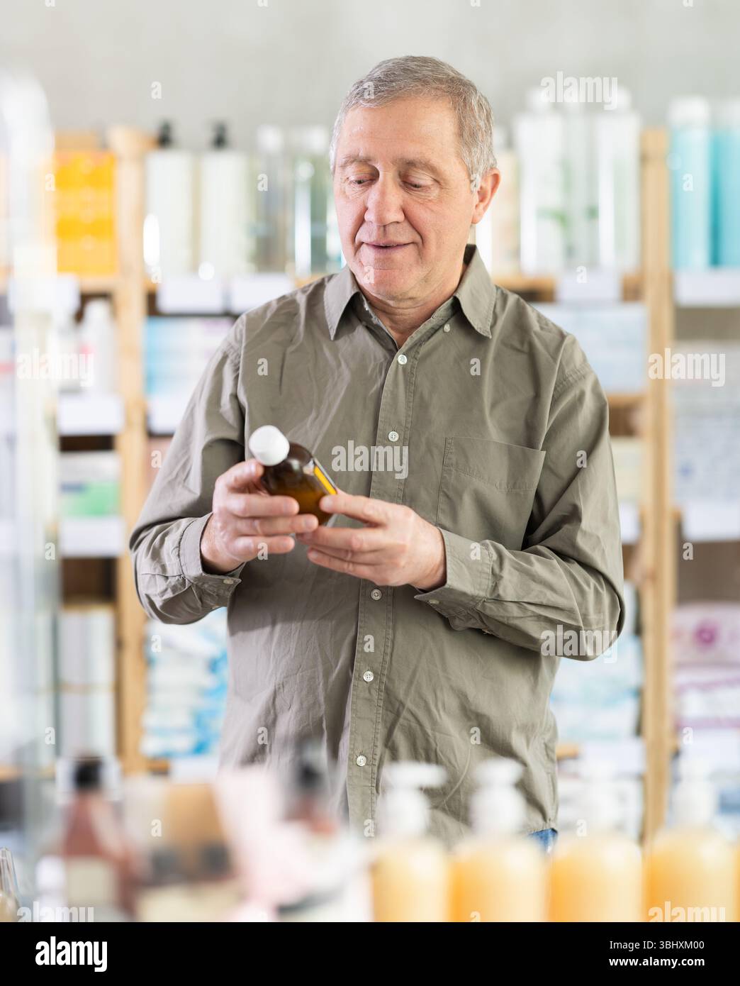Elderly man choosing syrup at pharmacy Stock Photo - Alamy