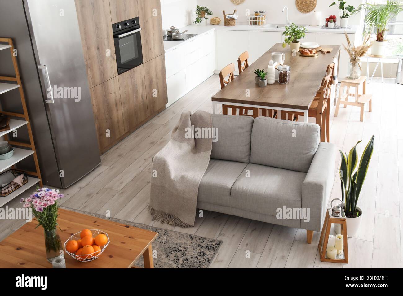 Interior of light open plan kitchen with fridge and grey sofa Stock ...