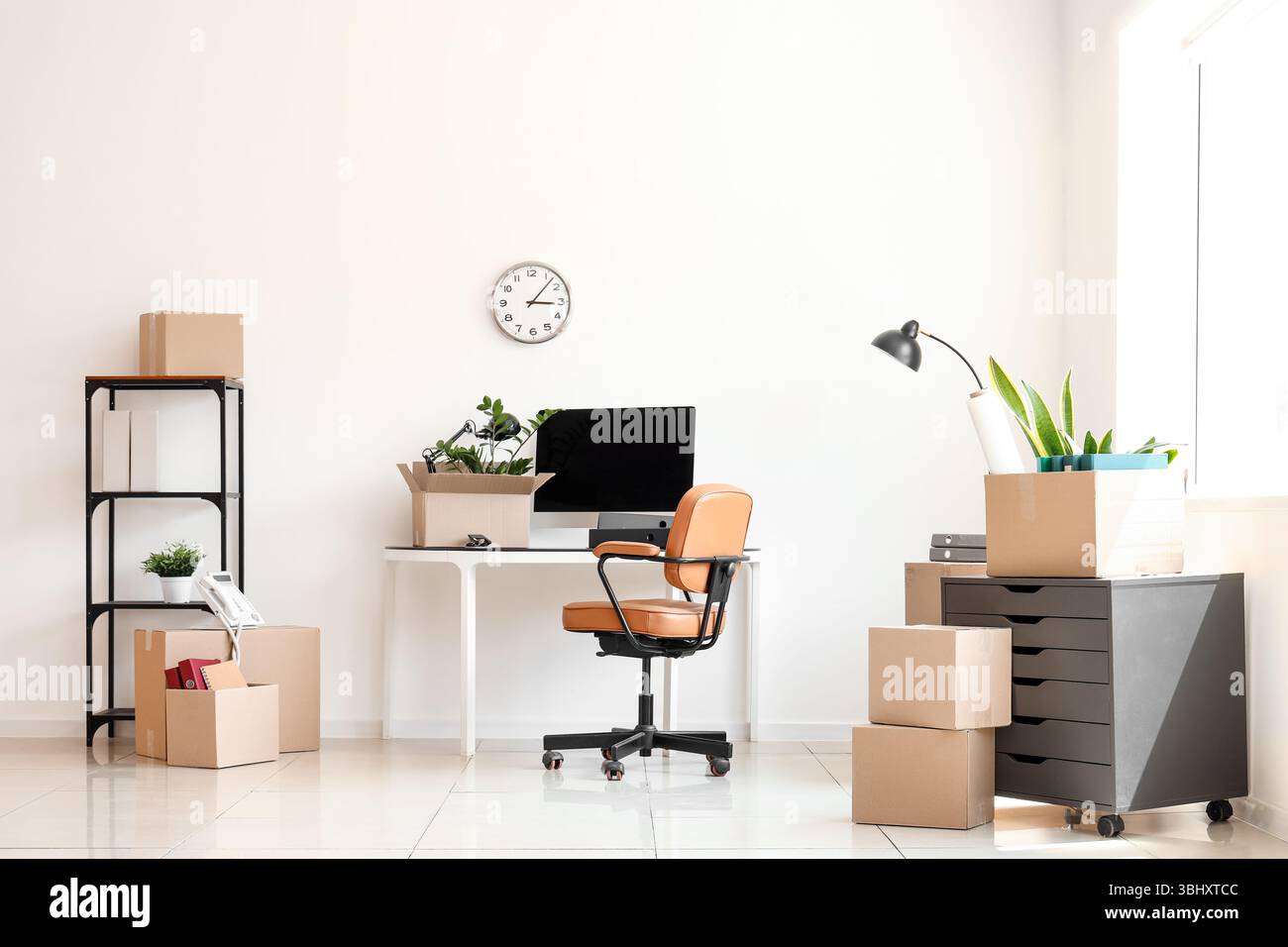 Interior of office with workplace, shelf unit and cardboard boxes on ...