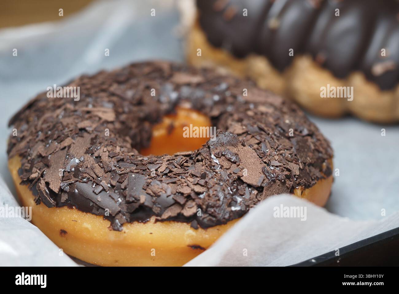 Chocolate donut topped with flakes on display Stock Photo - Alamy