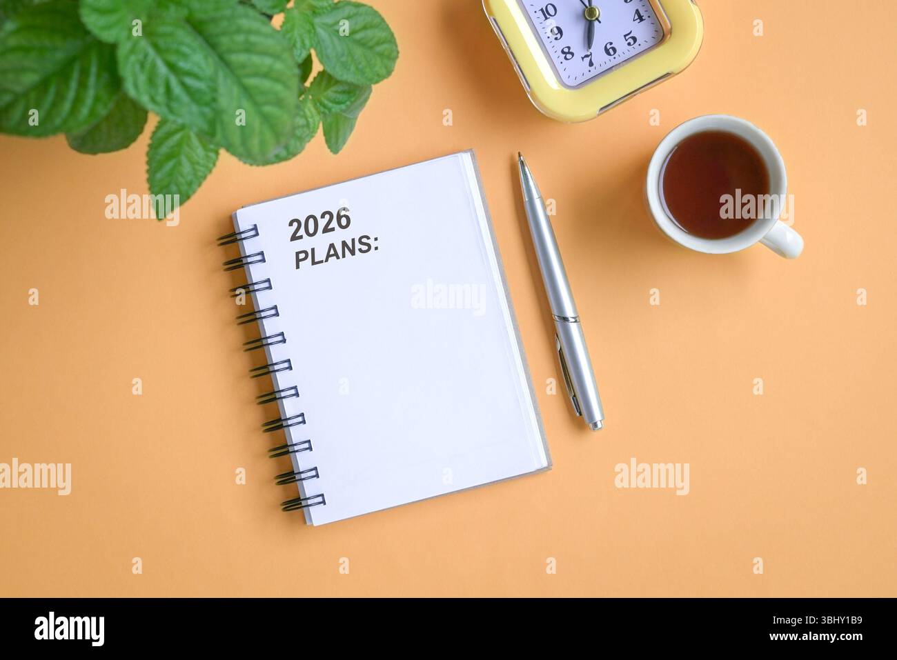 2026 plans on notepad, next to cup of coffee, clock, pen and green ...