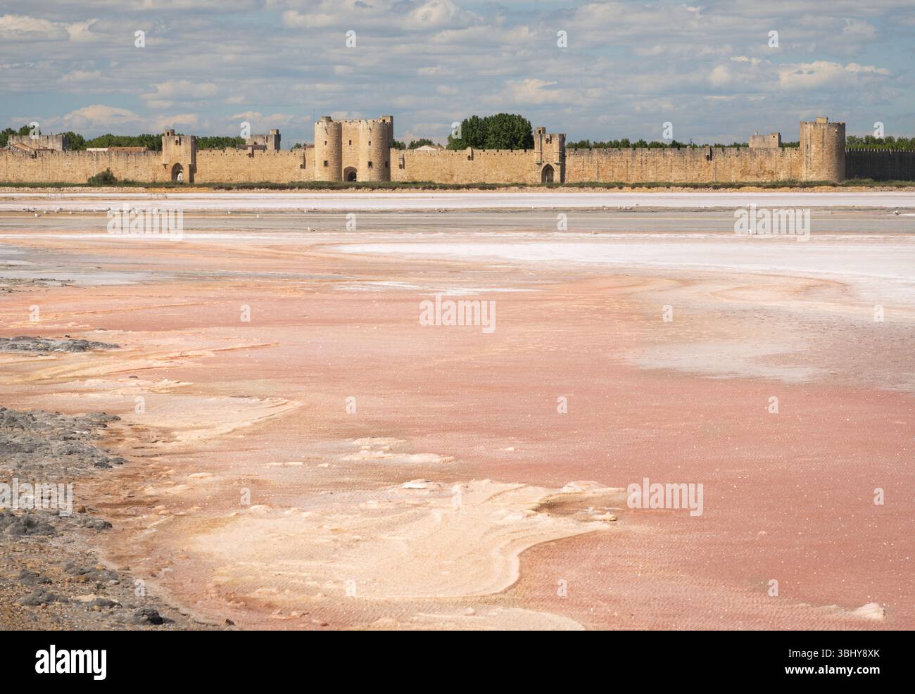 Walled medieval city of AIgues-Mortes surrounded by pink salt ponds and ...