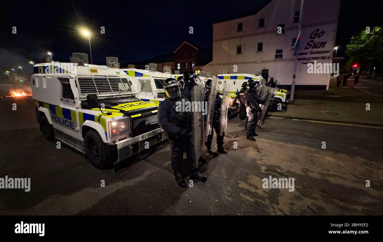 Officers from the PSNI form a barricade with riot shields and vehicles ...