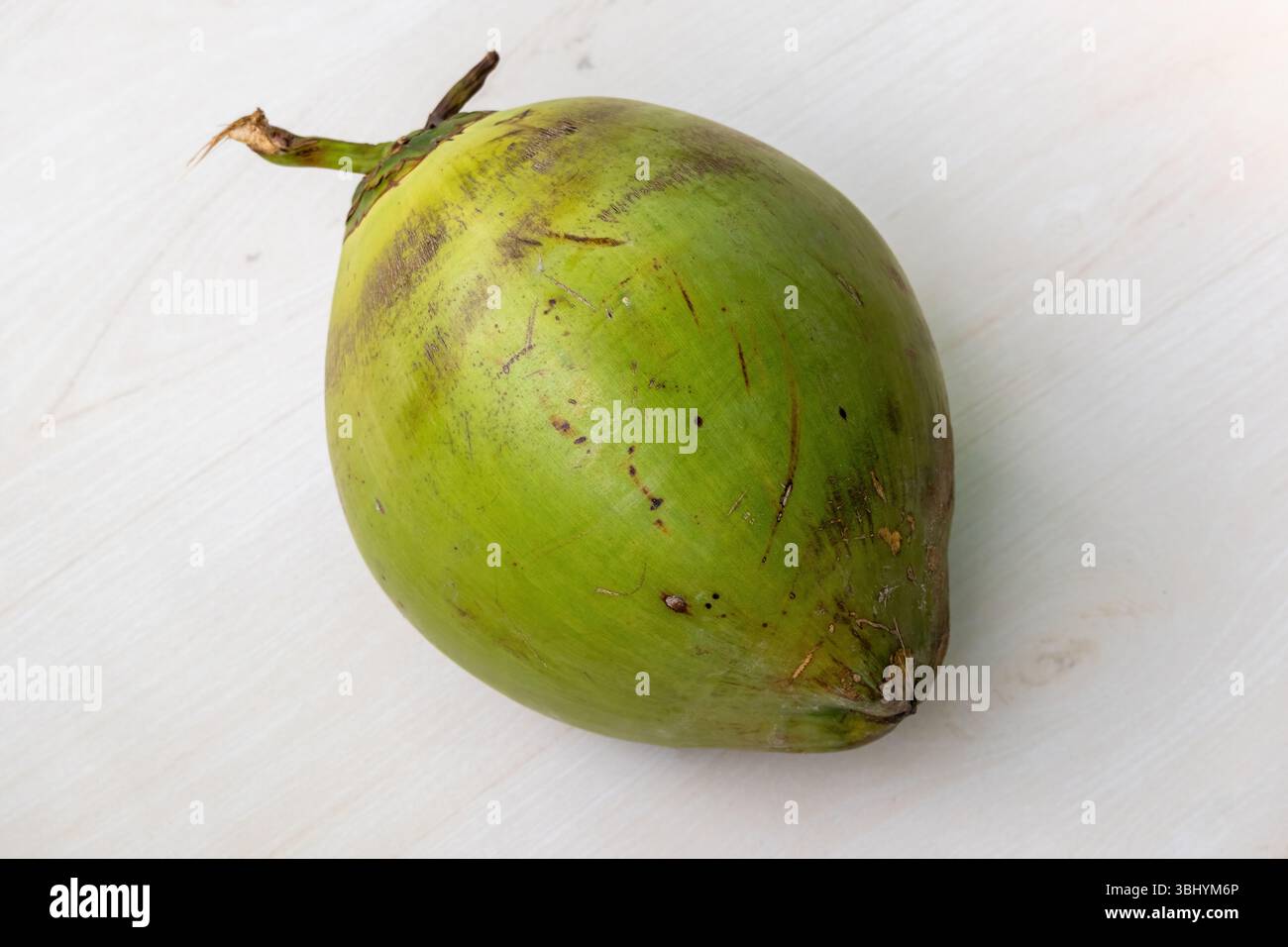 Fresh young green coconuts rest on a light wooden background. These ...