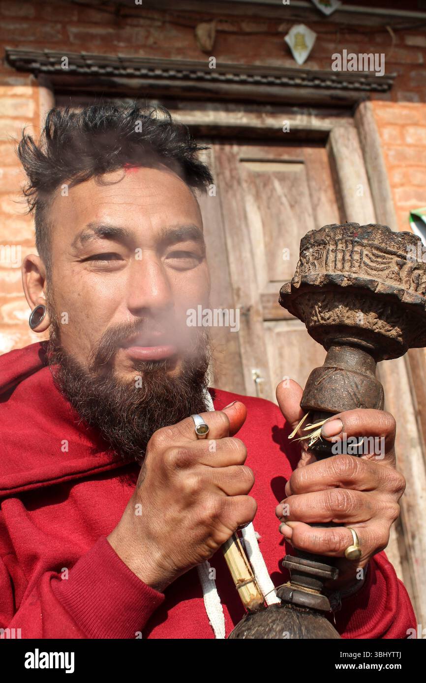 A Newar man preparing his traditional clay hookah at the Hanuman Ghat ...