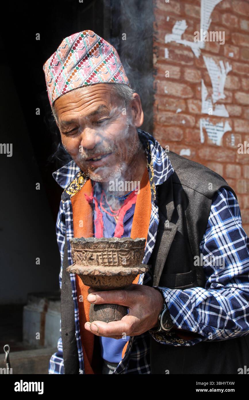 A Newar man preparing his traditional clay hookah at the Hanuman Ghat ...