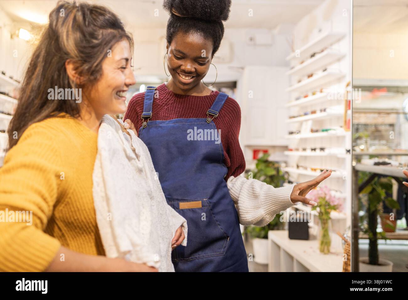 A smiling shop assistant helps a customer in a fashion boutique ...