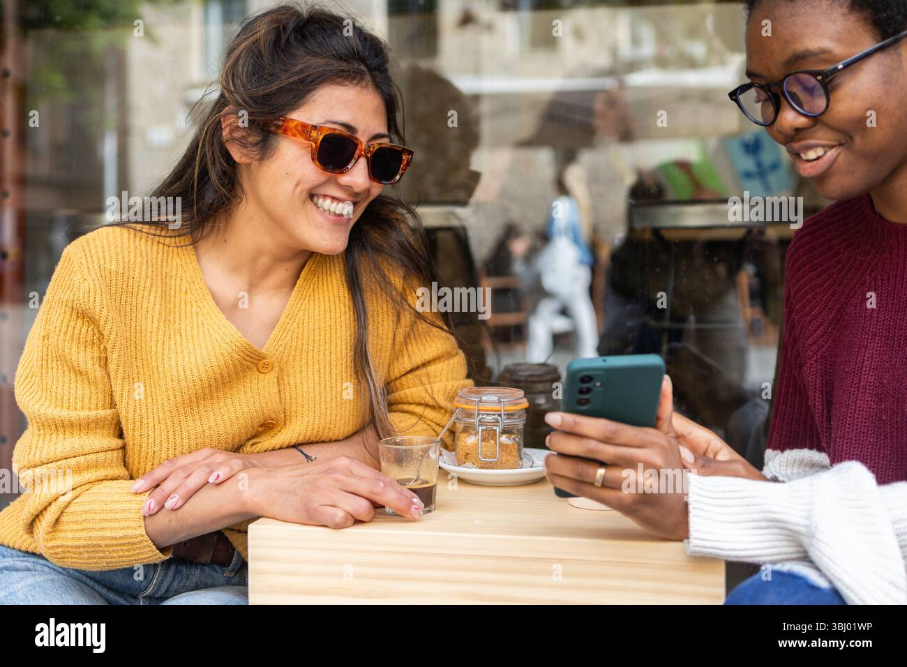 Two friends enjoy a sunny day at a cafe, sharing coffee and smiles. One ...