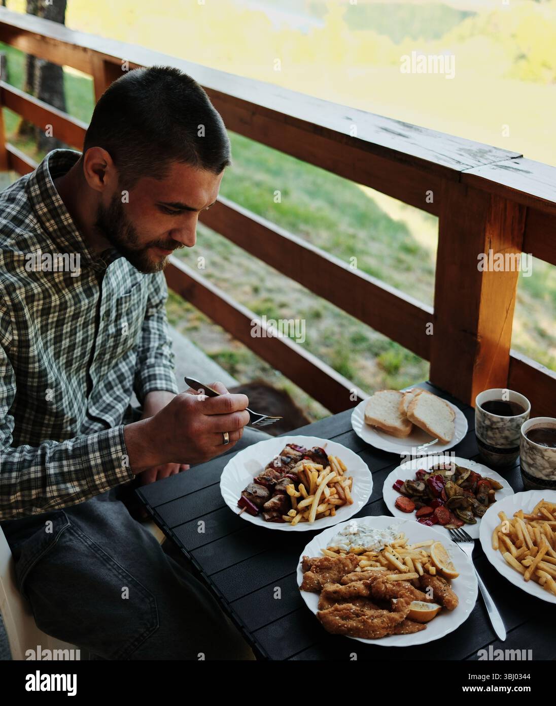 Man enjoying a traditional Balkan lunch outdoors, sitting by a wooden ...