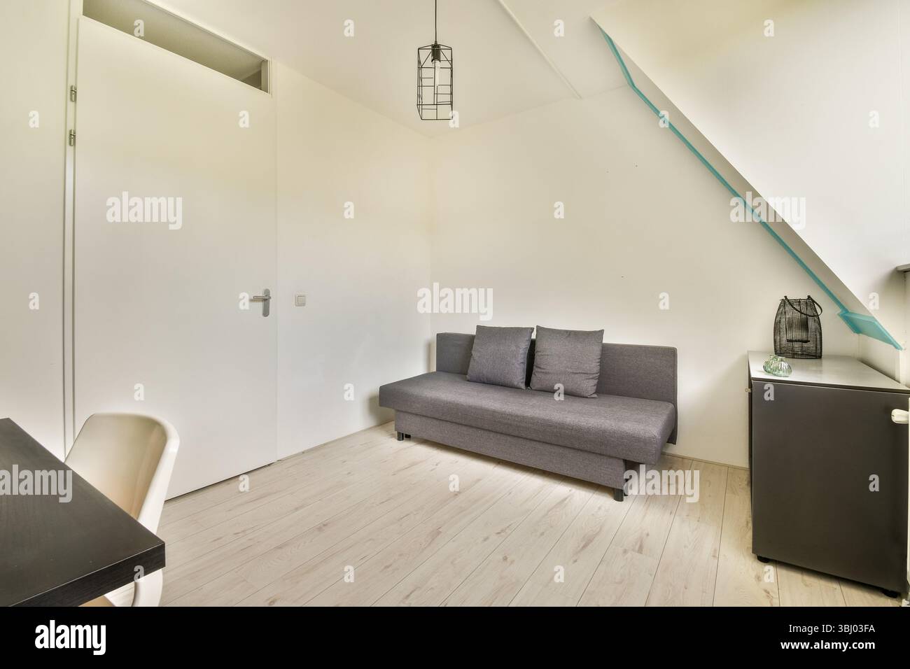 A chic and simple interior space featuring a grey sofa, light wood ...