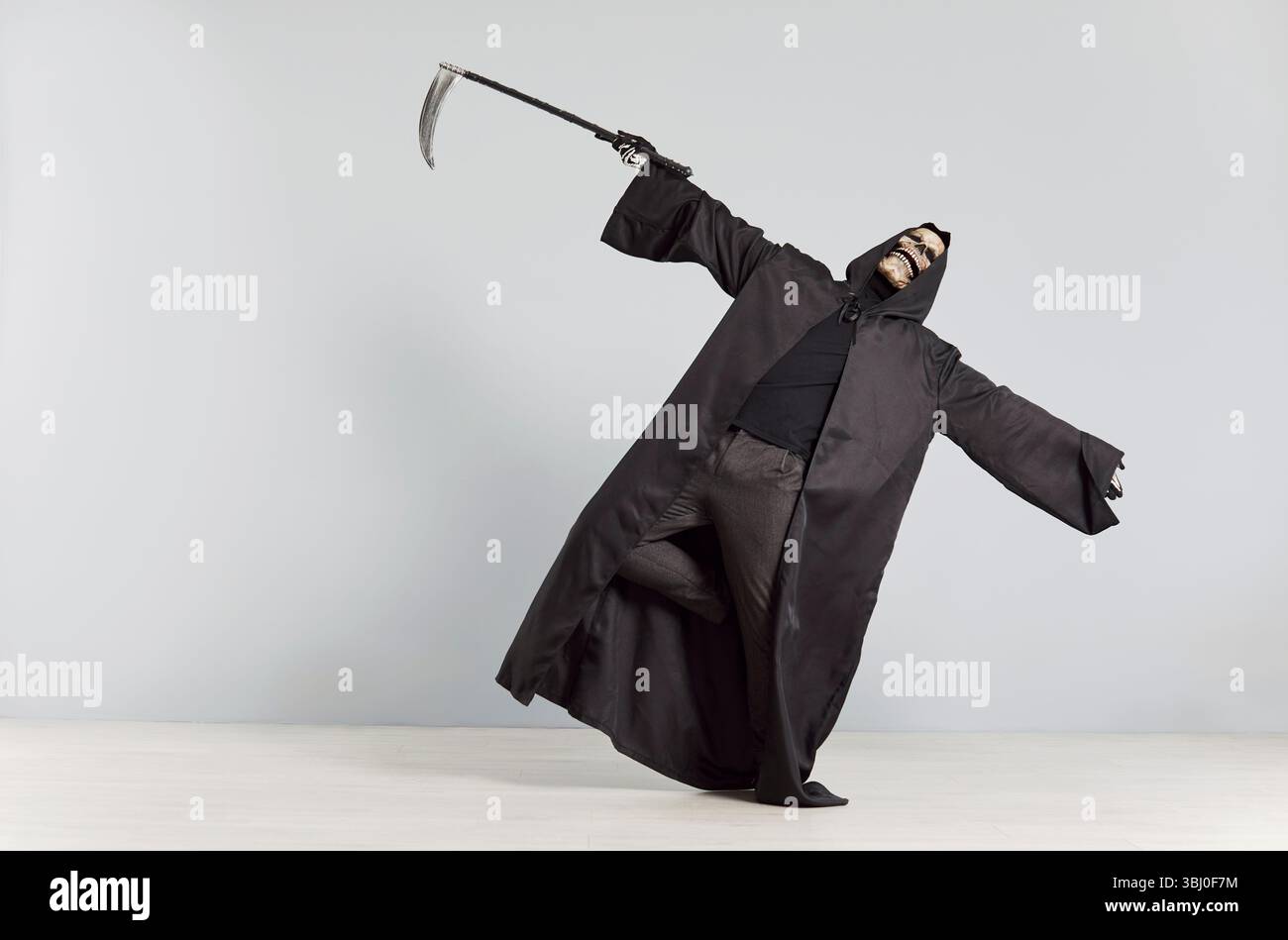 Man in grim reaper death costume having fun isolated on studio gray ...