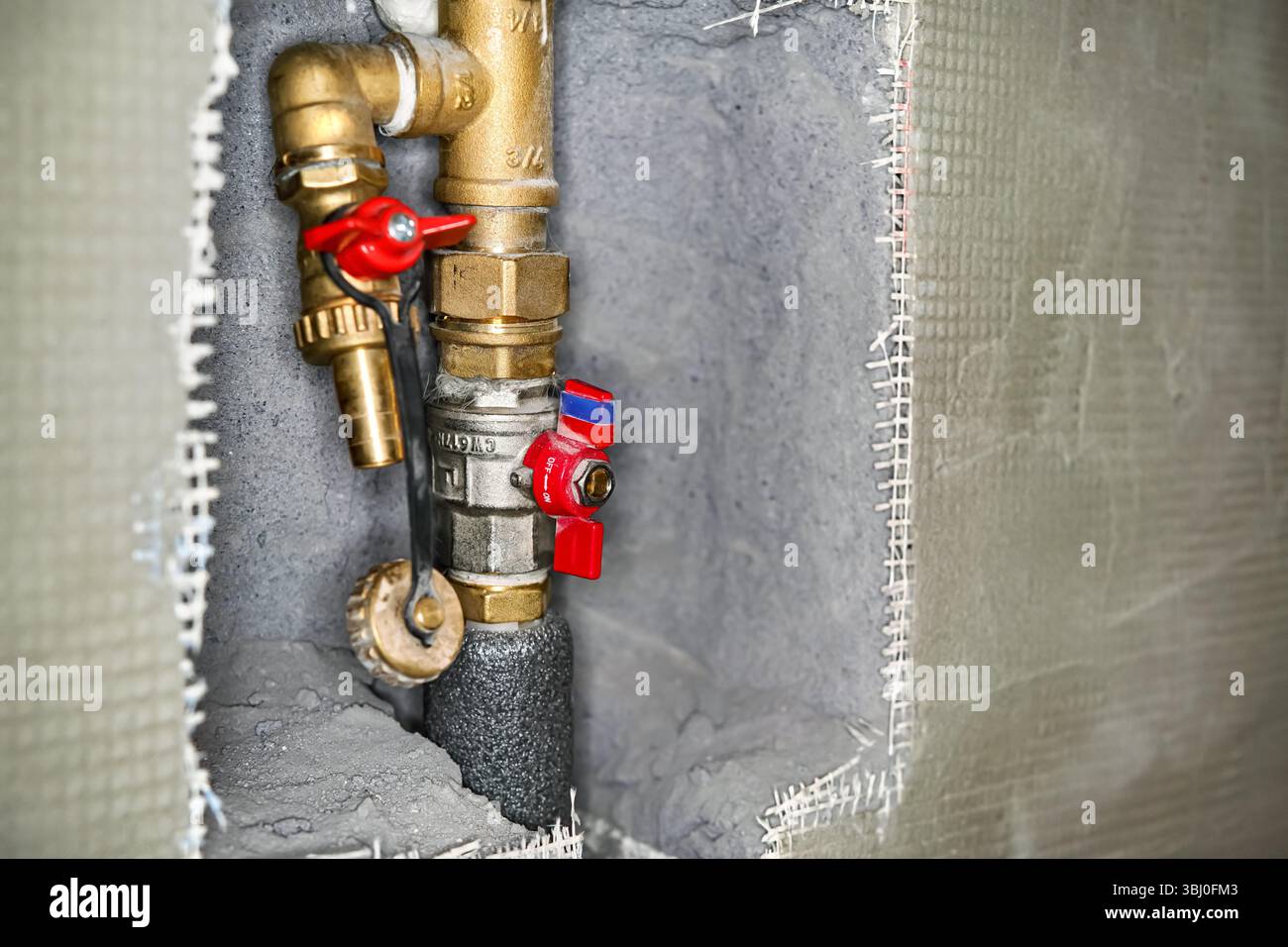 Newly installed brass water pipes plumbing with red tap fittings, gray ...