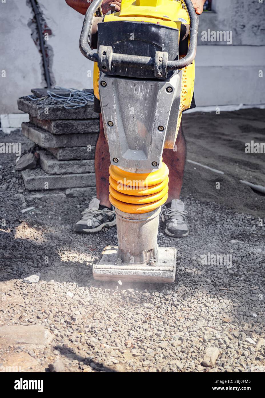 Industrial worker using gravel compactor or portable vibratory tamper ...