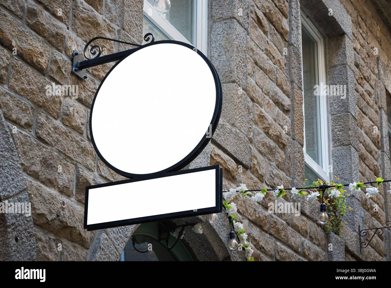 Blank shop signboard mockup on a stone building wall with round and ...