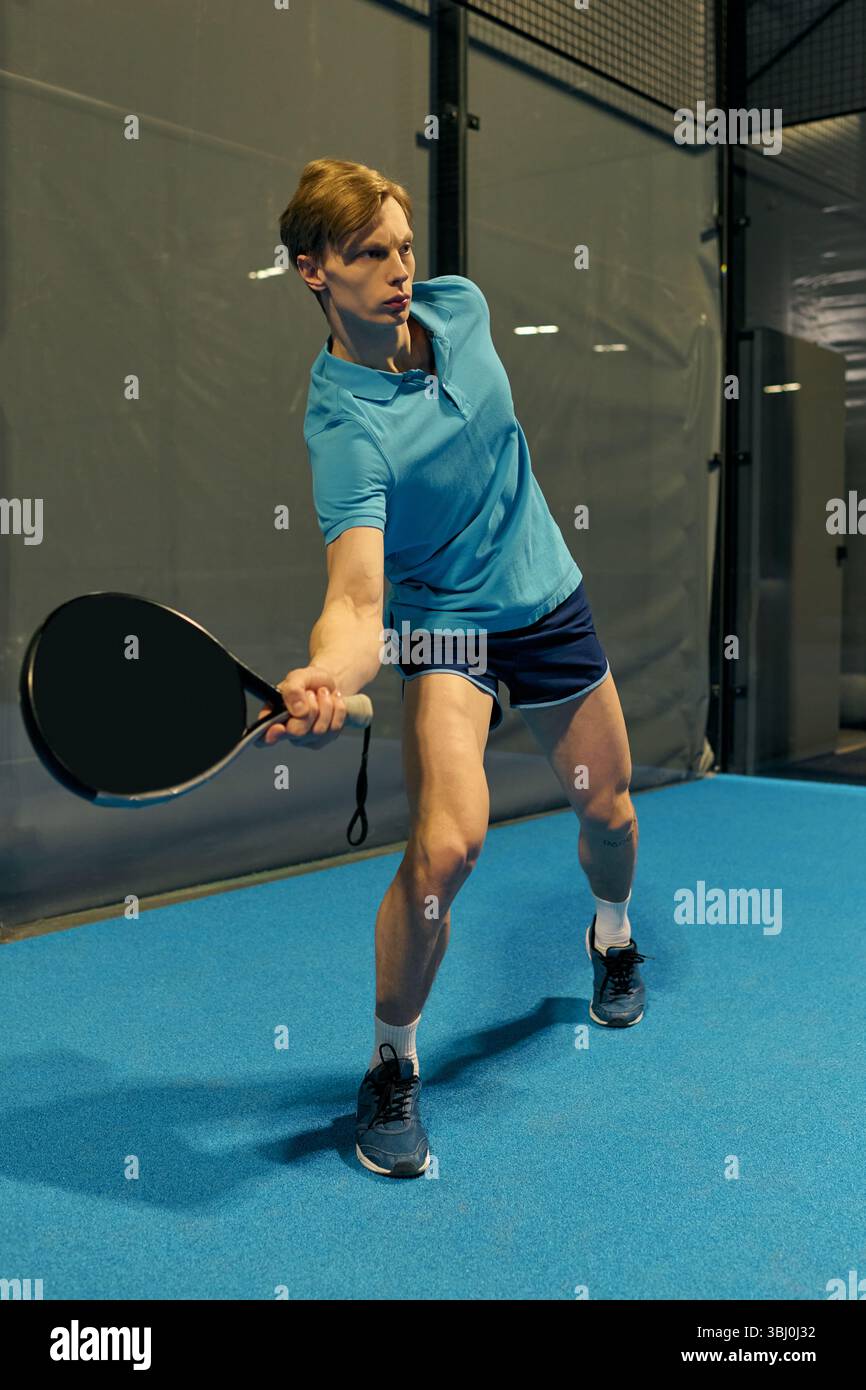 A young man showcases his athleticism while playing padel on a modern ...