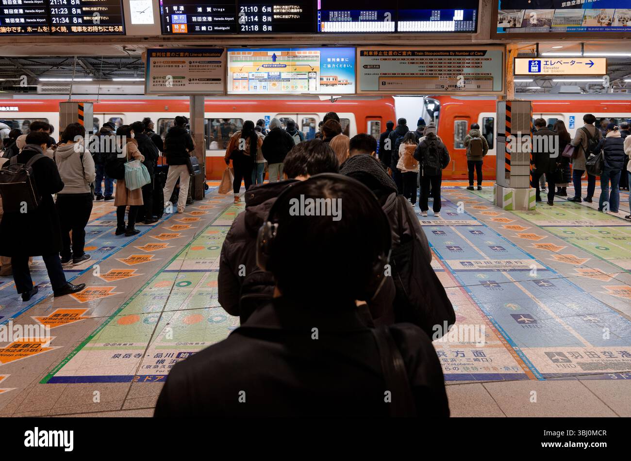 Commuters queue in orderly lines, waiting for the red Keikyu Line Stock Photo - Alamy